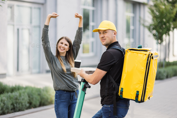 Food delivery courier giving order while standing on electric scooter ...