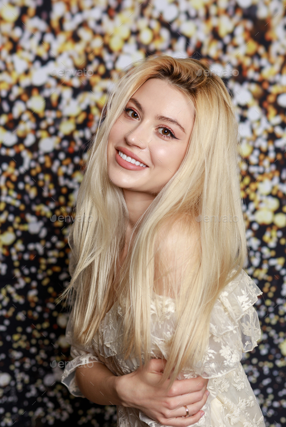 Adorable girl holding her hands to her arm and smiling to the camera ...
