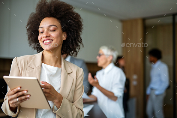 Portrait of young successful black woman working with tablet in office ...