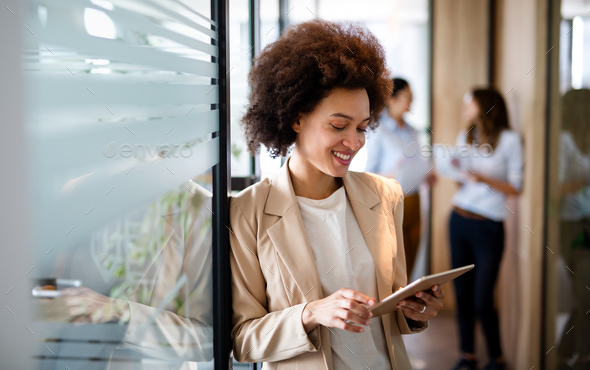 Portrait of young successful black woman working with tablet in office ...