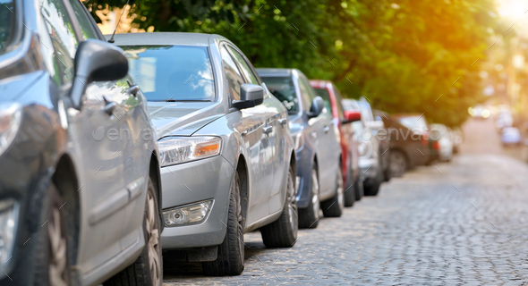 City traffic with cars parked in line on street side Stock Photo by bilanol