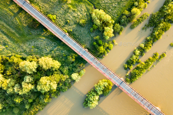 Aerial view of a narrow road bridge stretching over muddy wide river in ...