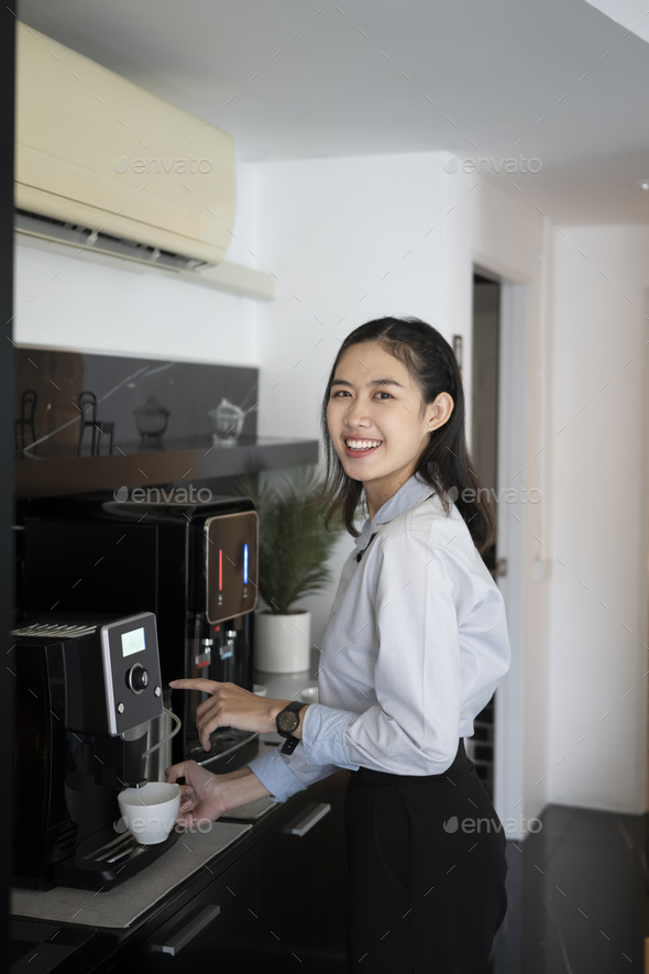 Portrait of happy young woman office worker making coffee from coffee ...