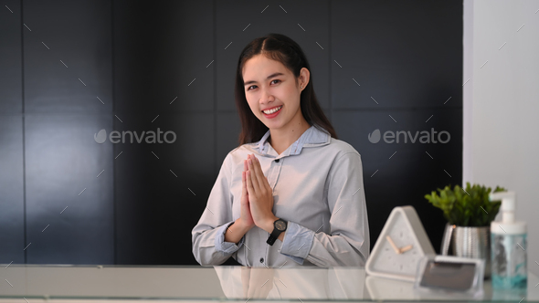 Young asian woman receptionist sitting at reception desk and raising ...