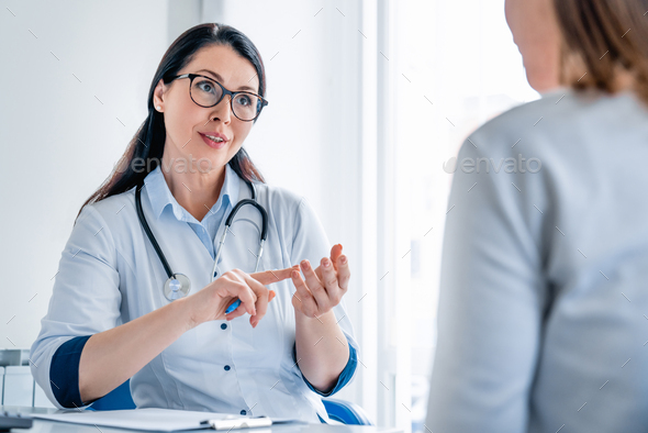 Smiling female doctor giving advice to female patient in cabinet Stock ...