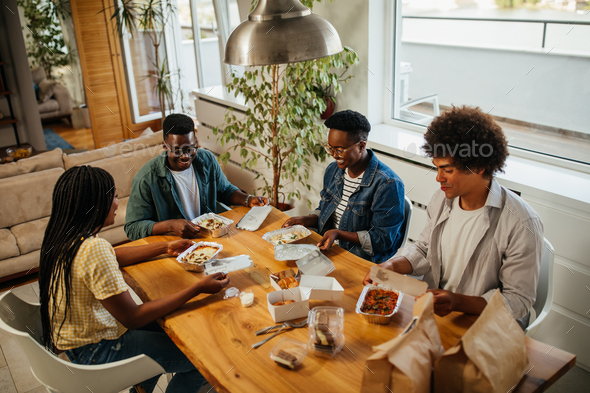 Black friends eating take out food at home Stock Photo by bernardbodo