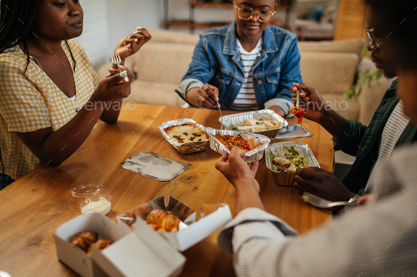 Young black friends eating take out food at home Stock Photo by bernardbodo