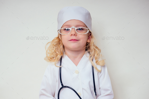 Adorable child girl uniformed as doctor wearing doctor's cap and ...