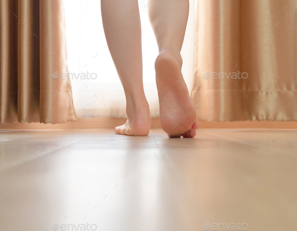 Woman feet legs on wood floor with curtain. Barefoot girl standing ...