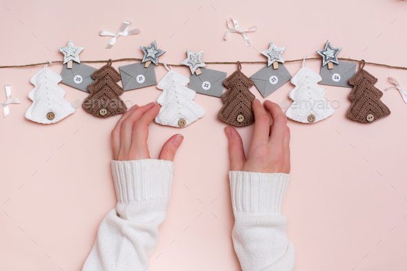 Knitted fir-trees and advent calendar in a row on a rope and female ...