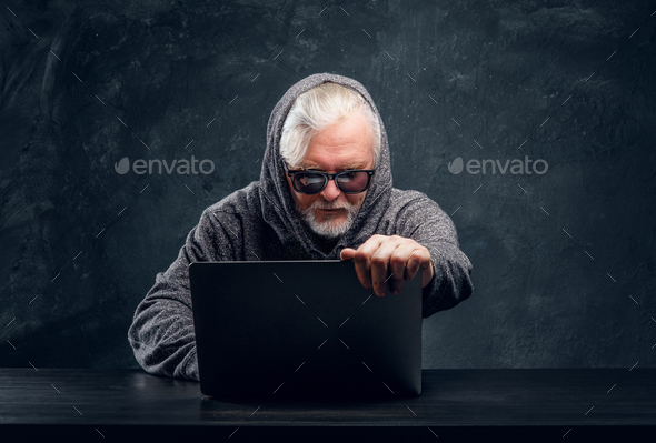 Old man hacker with laptop against dark background Stock Photo by fxquadro