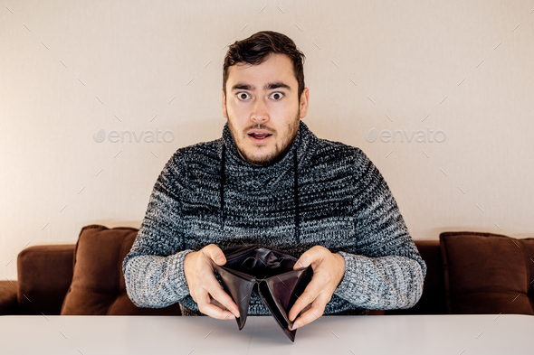 Man showing empty wallet. Depressed Young Man Looking At Empty Wallet ...