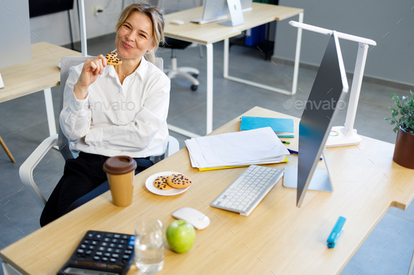 Adult female office worker eating cookies during coffee break Stock ...