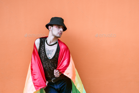 Man with lgbti flag on shoulders with casual pose while looking right ...