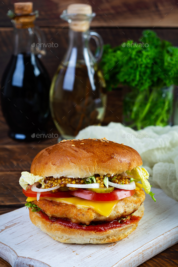 Tasty chicken burger with lettuce, cheese, tomato and pickle. Fast food ...