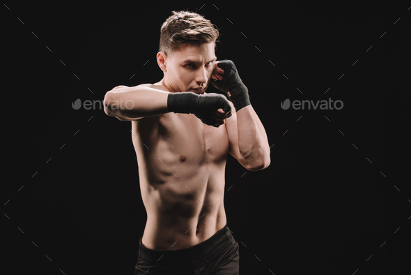 strong confident mma fighter in bandages doing punch isolated on black ...
