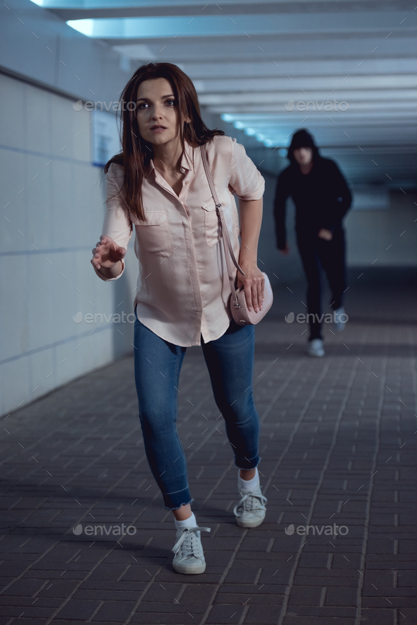 frightened woman running away from thief in underpass Stock Photo by ...