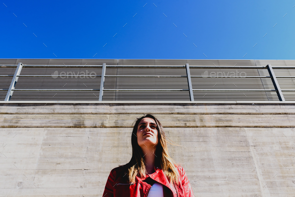 Young woman seen from below while she looks afar in industrial ...