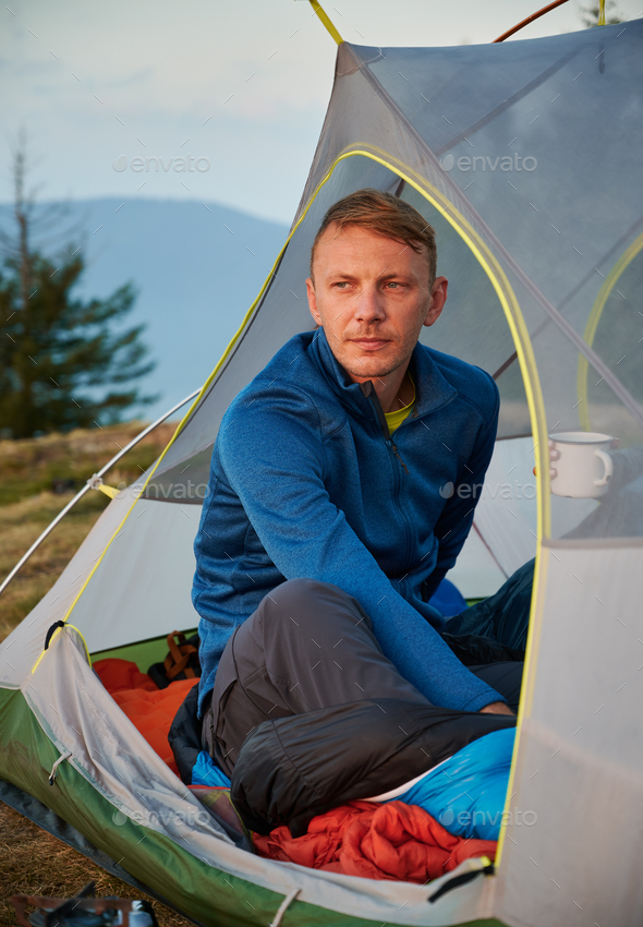 Male camper relaxing in tent in the mountains. Stock Photo by anatoliy_gleb