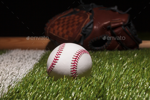 Baseball on grass field low angle close up with mitt and bat soft focus ...