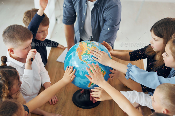 Touching the Earth globe. Group of children students in class at school ...