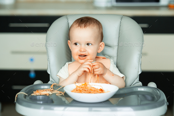 domestic scene with a baby little boy eating spaghetti. Stock Photo by ...