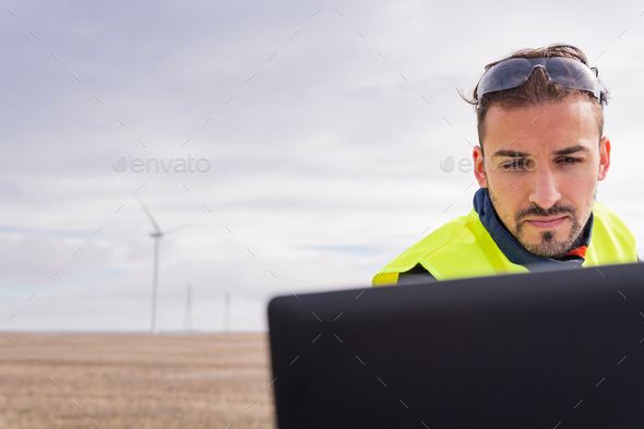 Wind farm operator working with his laptop in nature. Concept of zero ...