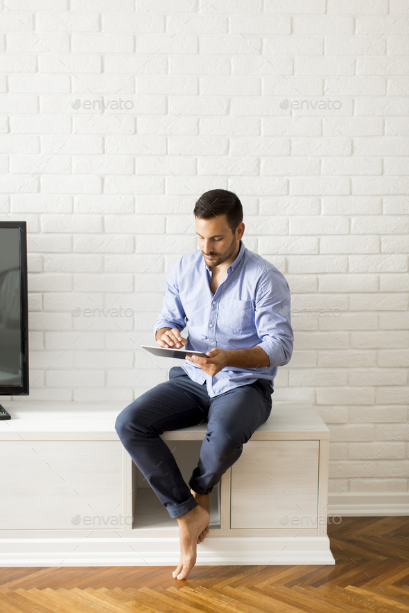 Happy man browsing in a tablet sitting on commode at home Stock Photo ...