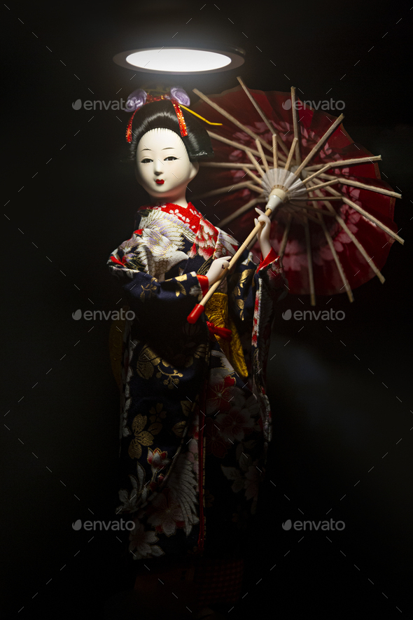 Traditional Japanese Geisha figure with overhead light and dark ...