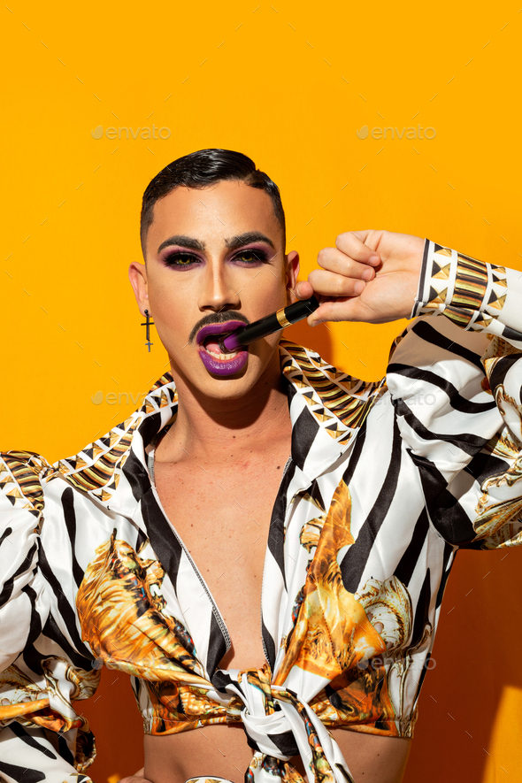 beautiful drag queen portrait biting lipstick on a yellow background ...