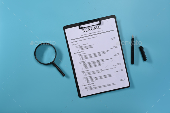 Flat lay magnifying glass and resumes applicants on blue background ...