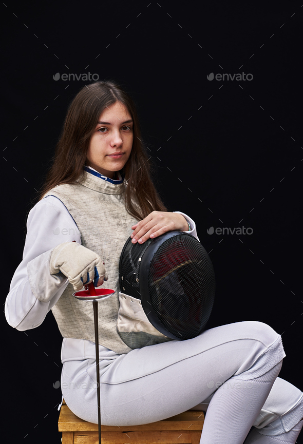 Portrait of woman dressed in white fencing costume practicing with the ...