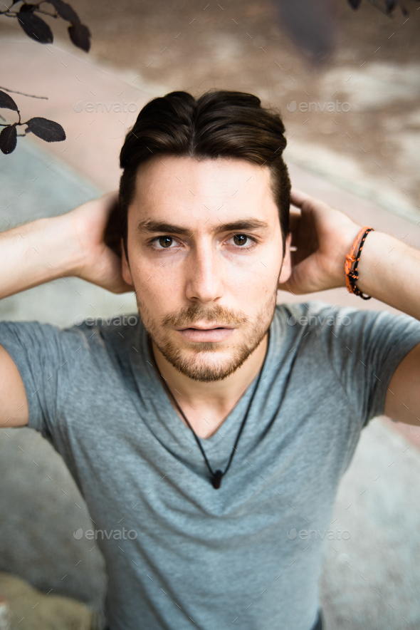 Handsome male model in gray shirt looking at camera with calm pose ...