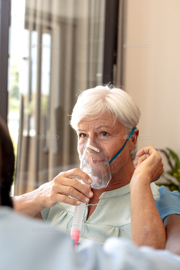 Caucasian senior woman using oxygen mask sitting on a wheelchair at ...