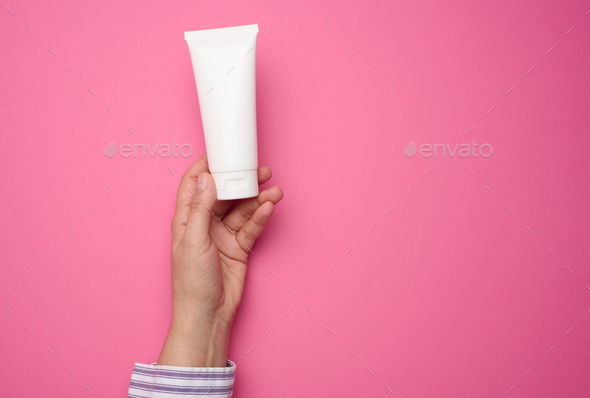Female hand holding white plastic tube. Packaging for cream, gel, serum ...