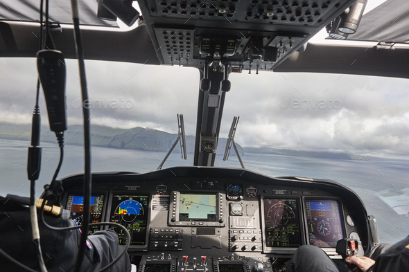 Helicopter cabin with pilots flying over Faroe Islands coastline ...