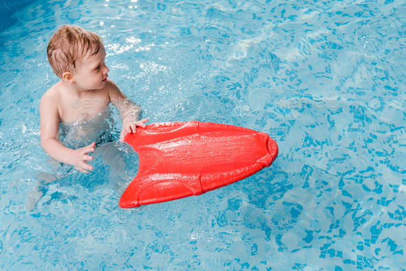 cute toddler boy swimming with flutter board in swimming pool Stock ...