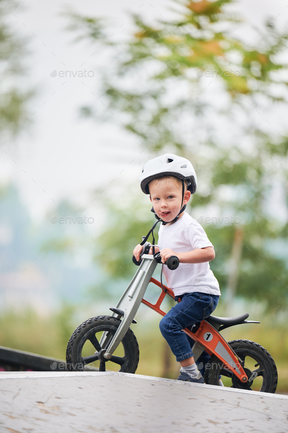 Toddler kid learning to ride on run bicycle at skate park. Stock Photo ...