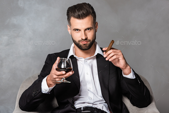 successful businessman in black suit sitting in armchair with cigar and ...