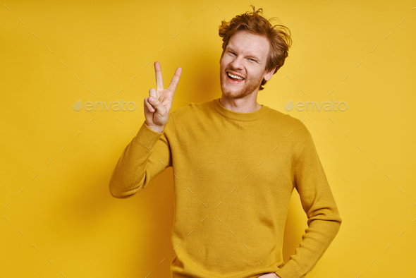 Cheerful redhead man gesturing welcome sign while standing against ...