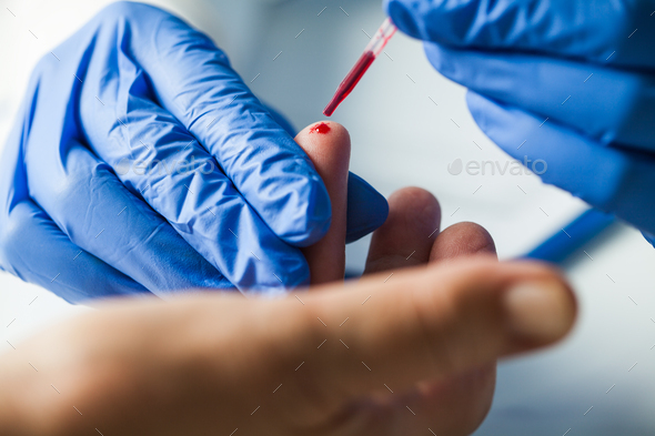 Medical technician EMS doctor taking finger prick PRP patient blood ...