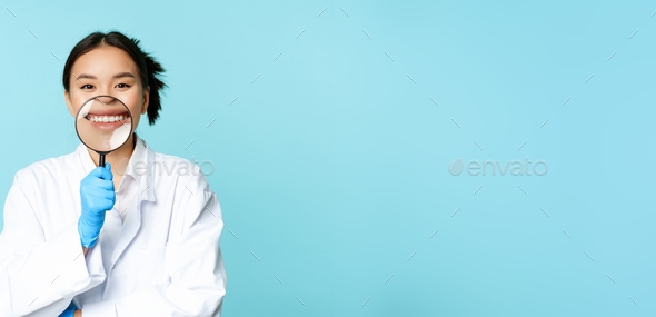 Funny asian female physician, doctor showing her smile with magnifying ...