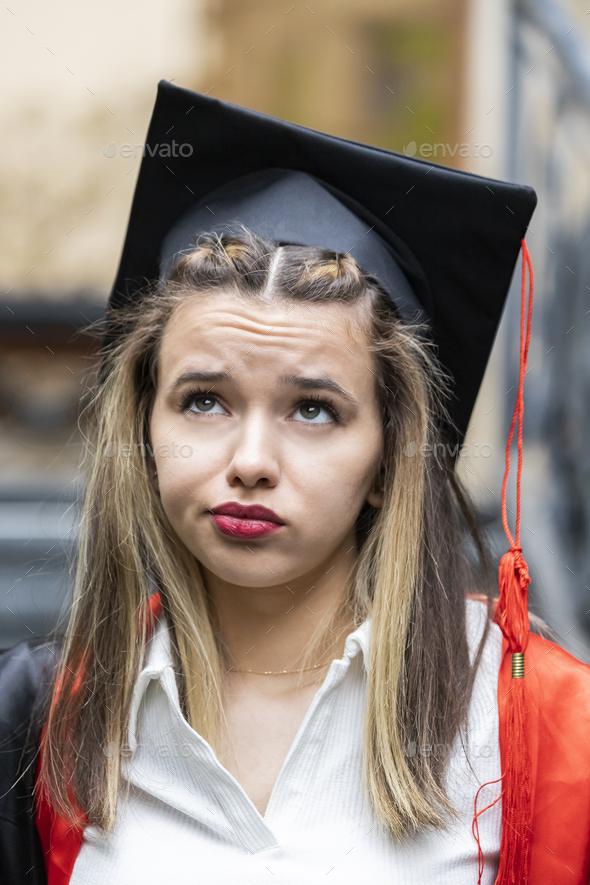 Photo of adorable blonde student wearing graduation cape and seems ...