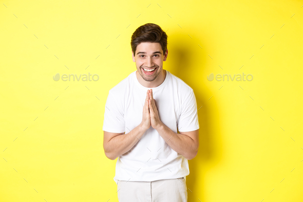 Handsome guy saying thank you, bowing and holding hands in namaste ...