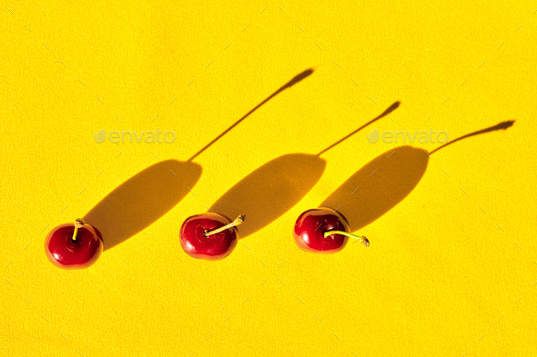 Top view of three red cherries with shadow isolated on a yellow ...