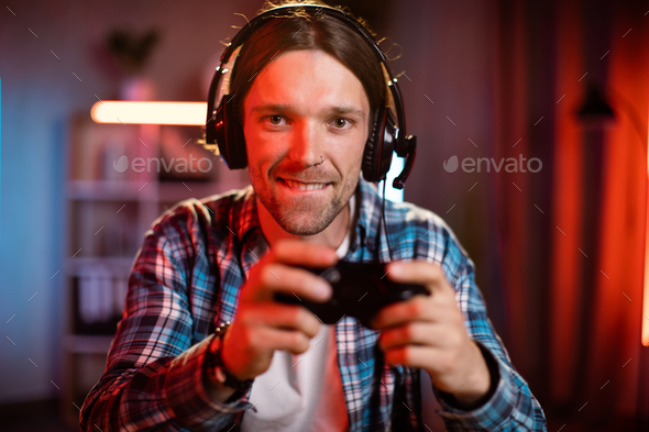 Portrait of cheerful caucasian guy in headset using remote console for ...