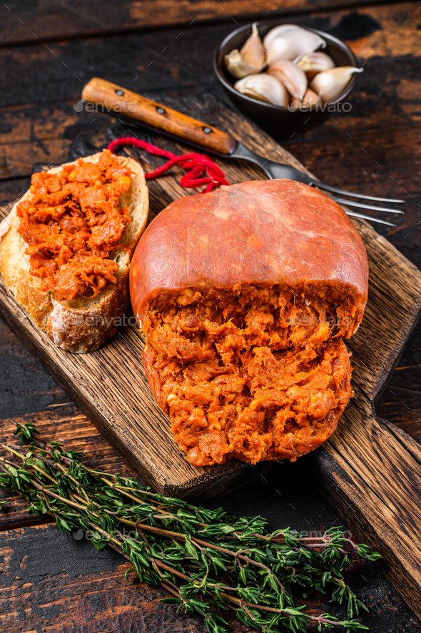 Sobrassada cured pork meat sausage on bread slice. Dark wooden ...