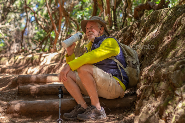 Happy elderly traveler man with cap and backpack enjoying hike in ...