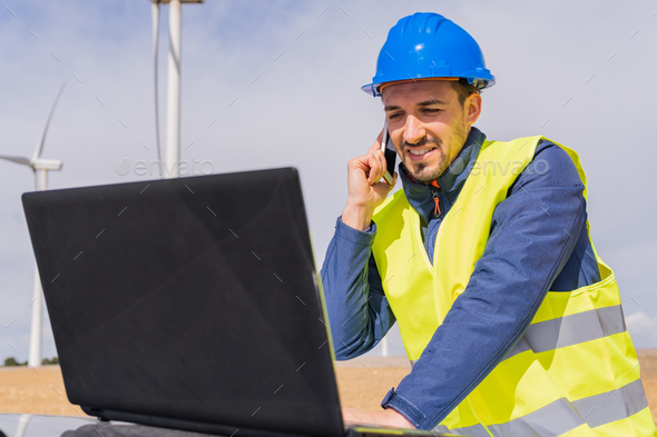 Renewable power plant operator, working on his laptop while talking on ...