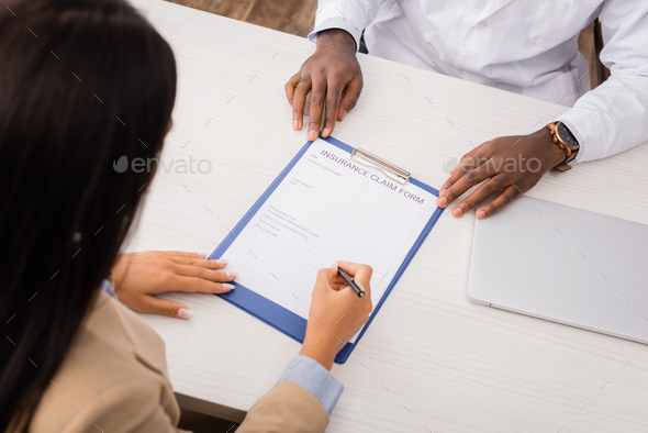 overhead view of patient signing insurance claim form near african ...